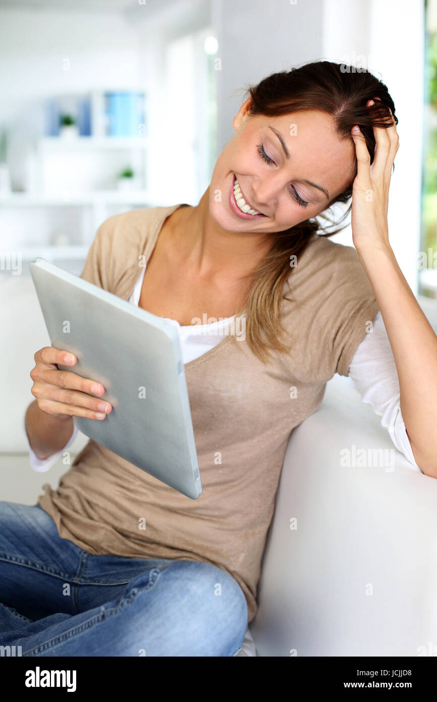 Young woman using electronic tablet sitting on sofa Stock Photo - Alamy
