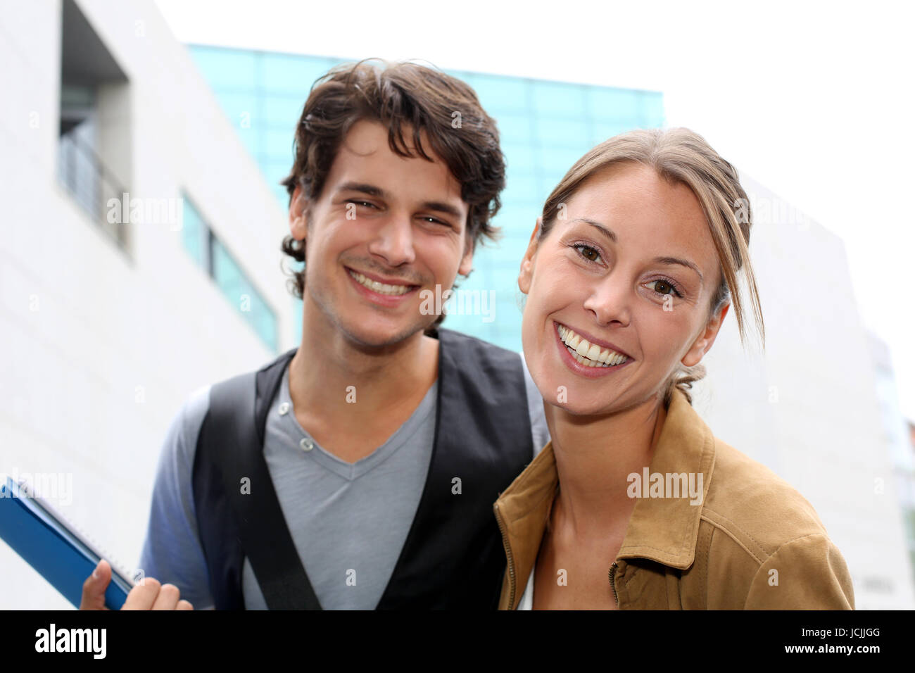 Cheerful couple of students standing on college campus Stock Photo - Alamy