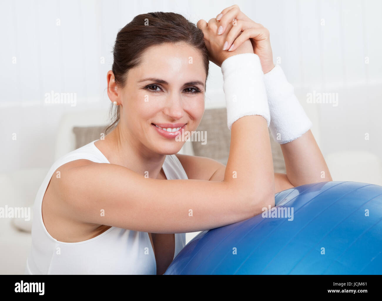 Close up of a happy smiling woman with a large blue pilates ball in a ...
