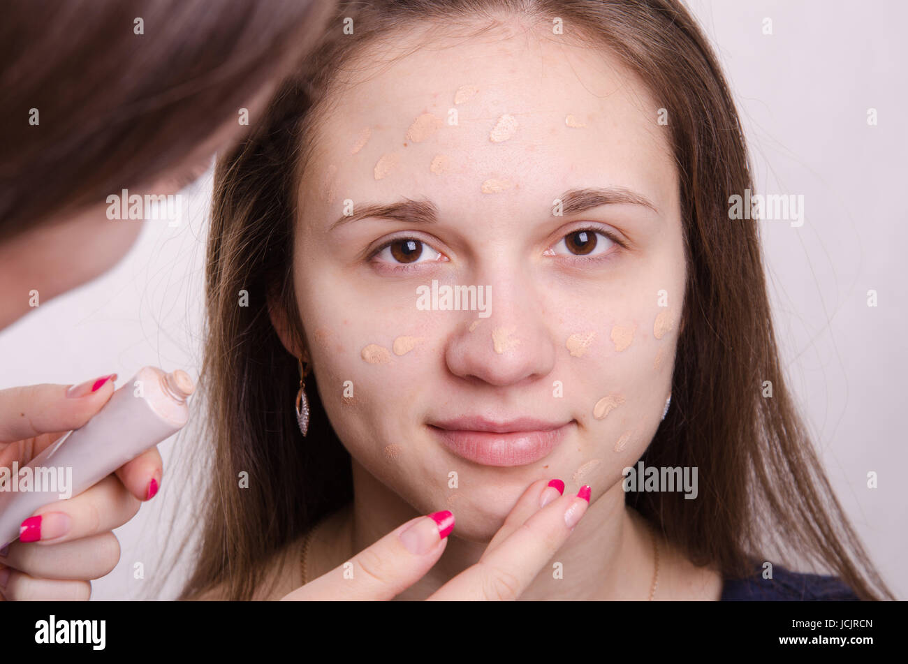 Makeup artist applies foundation of a beautiful young girl in the ...