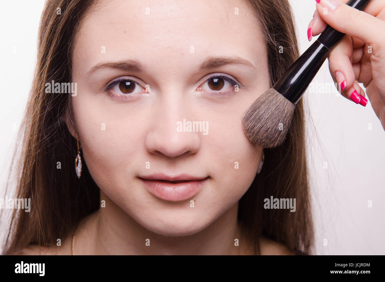 Makeup artist applies powder on the face of a beautiful young girl in ...