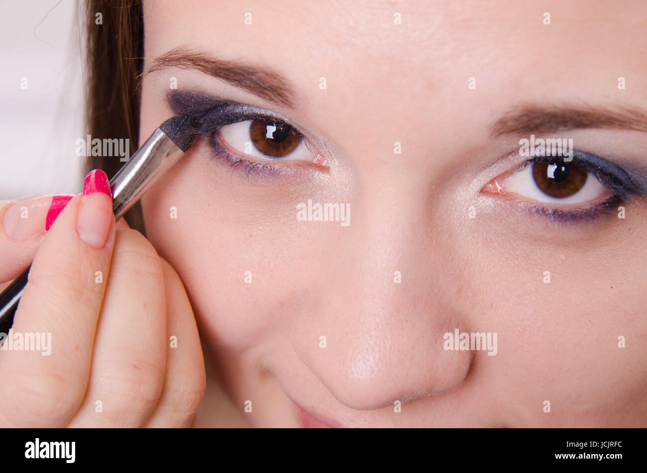 Makeup artist paints the eyelids of a beautiful young girl in the ...