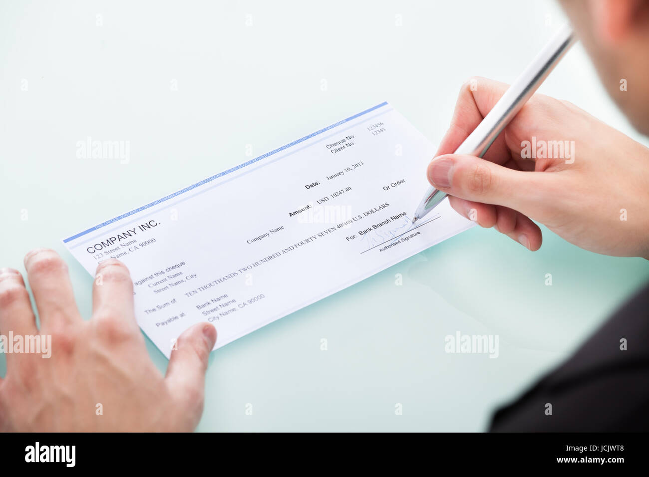 Young Businessman Filling Blank Cheque At Office Desk Stock Photo - Alamy