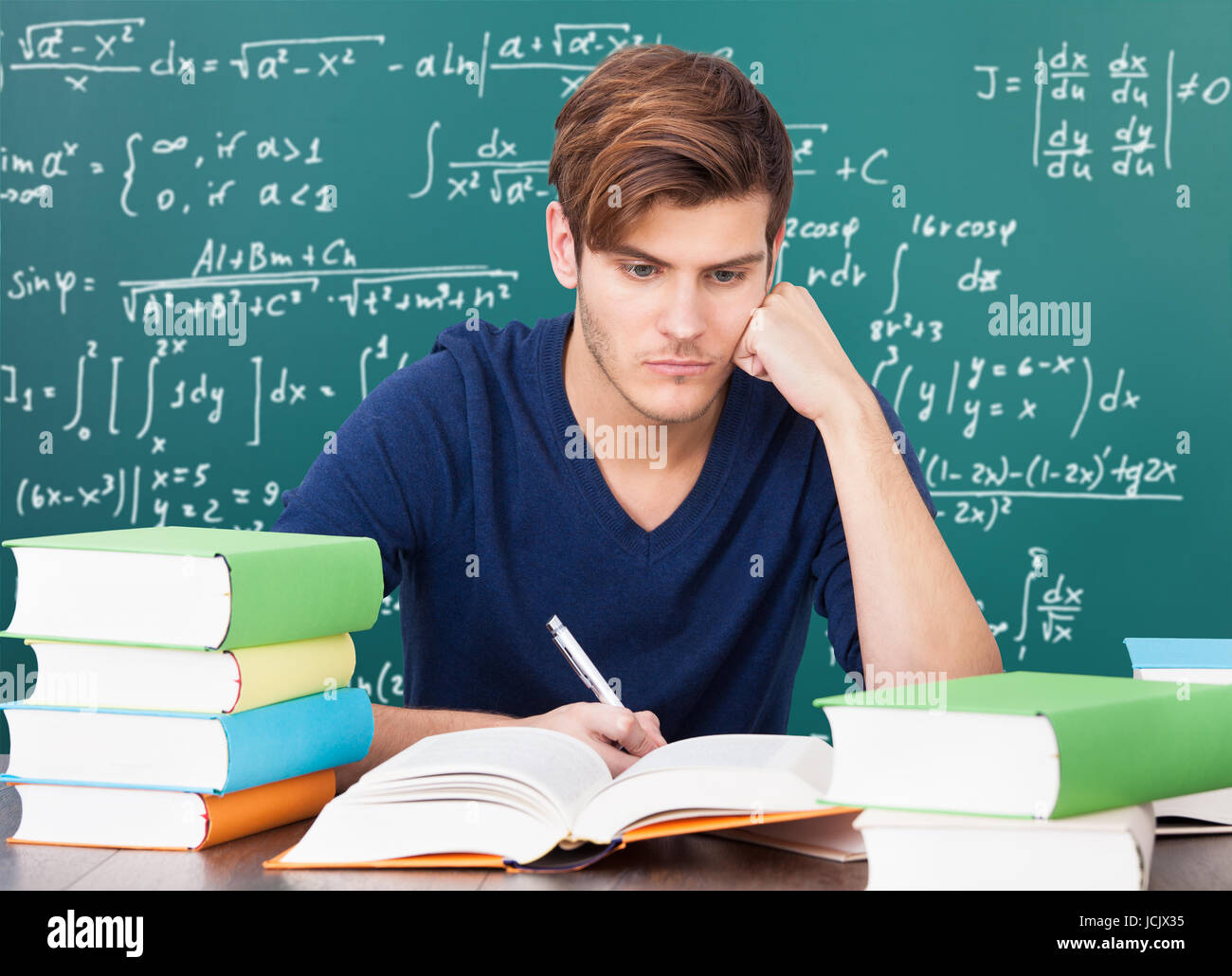 Serious Male Student Surrounded With Stack Of Books Stock Photo - Alamy
