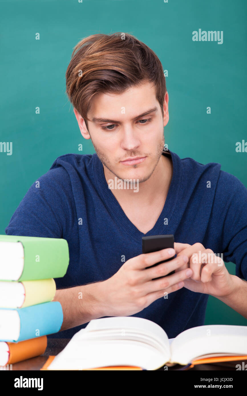 Portrait Of Male Student Using Cellphone While Studying Stock Photo - Alamy