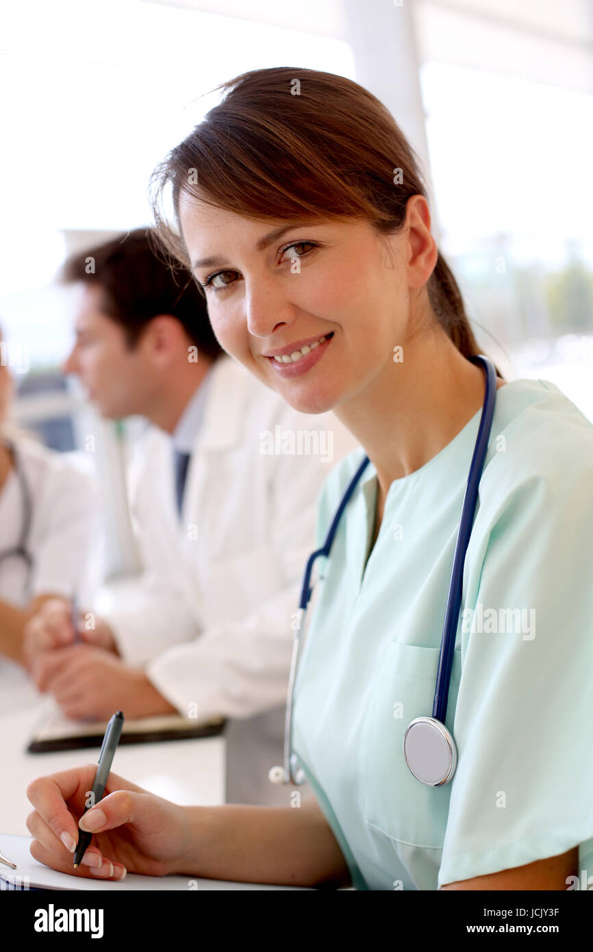 Attractive nurse working in hospital, people in background Stock Photo ...