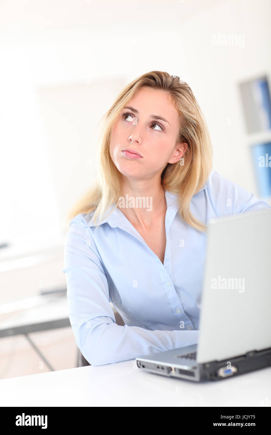 Blond woman at work with thoughtful look Stock Photo - Alamy