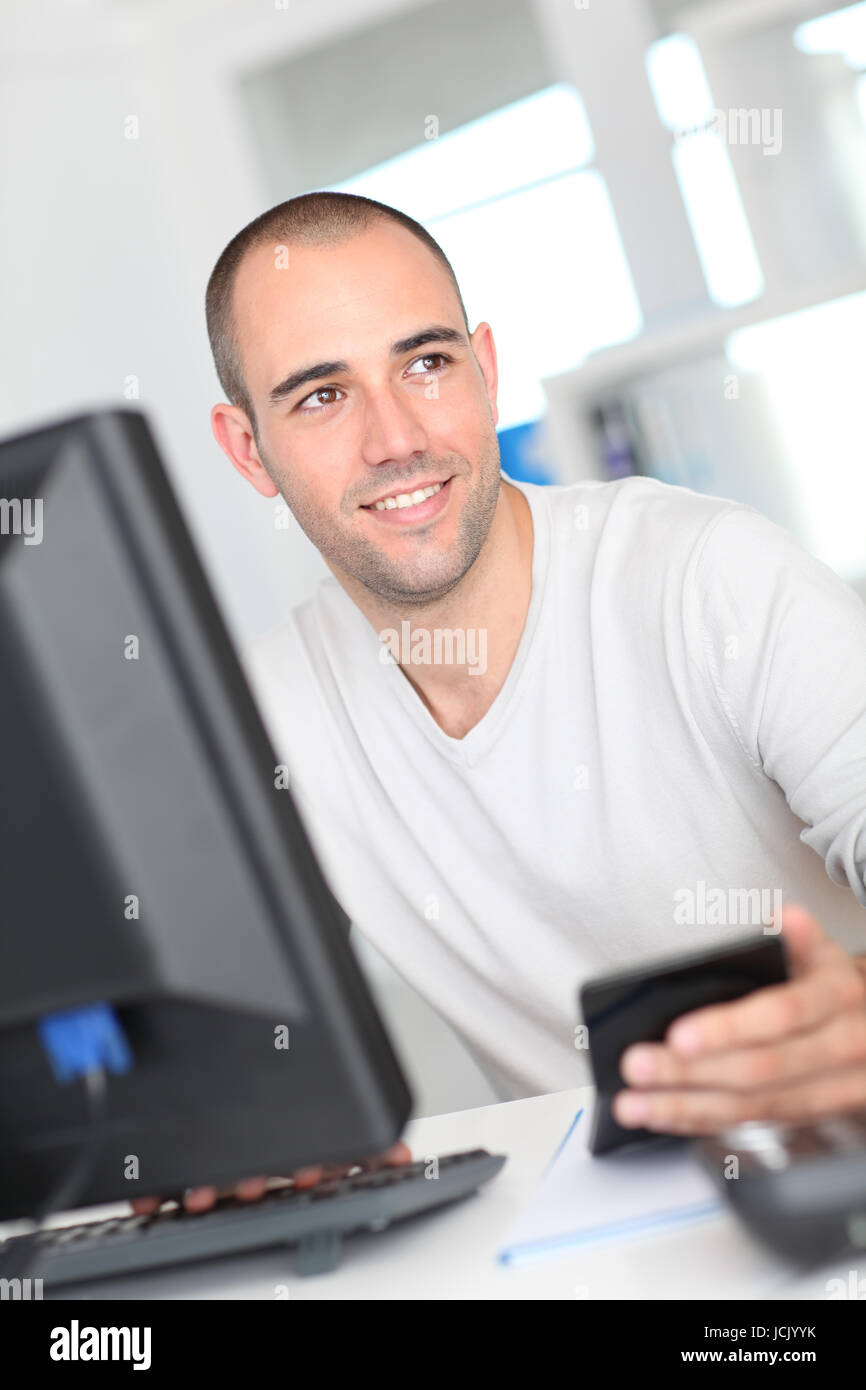 Smiling office worker sitting in front of desktop computer Stock Photo ...