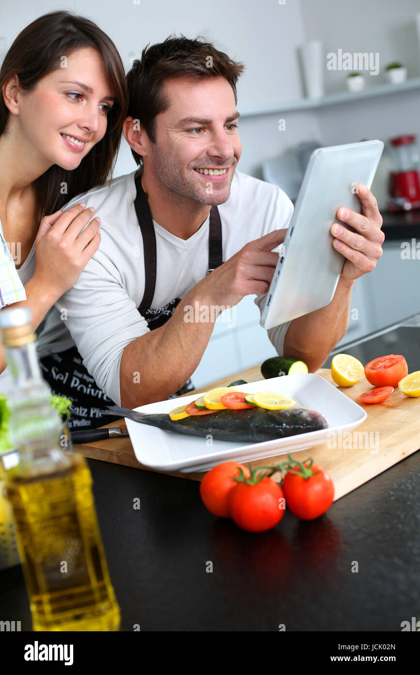 Couple in home kitchen using electronic tablet Stock Photo - Alamy