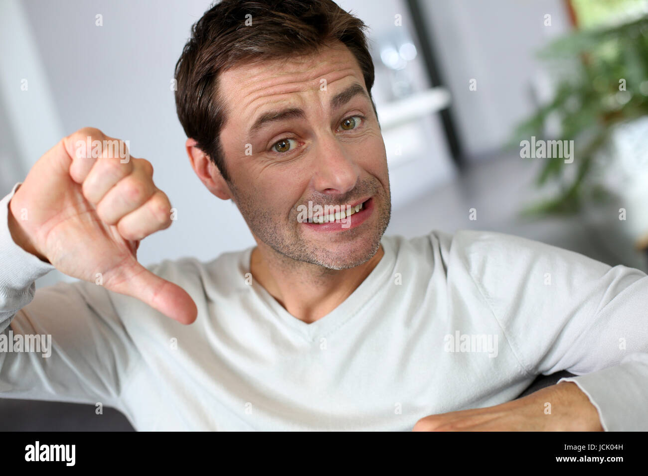 Discontented man showing thumb down Stock Photo - Alamy