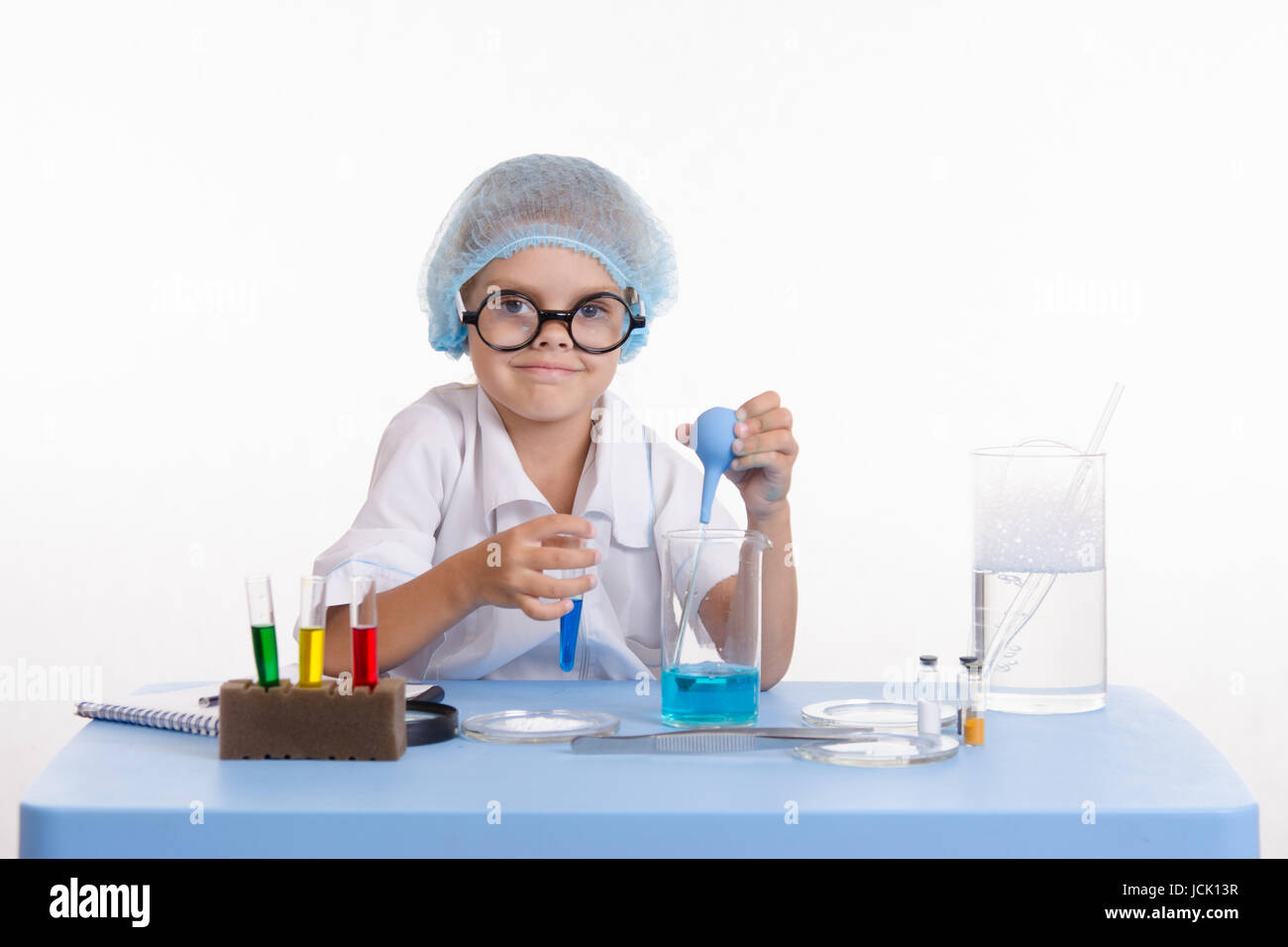 Chemist girl sitting at the table with the reagents in chemistry class ...