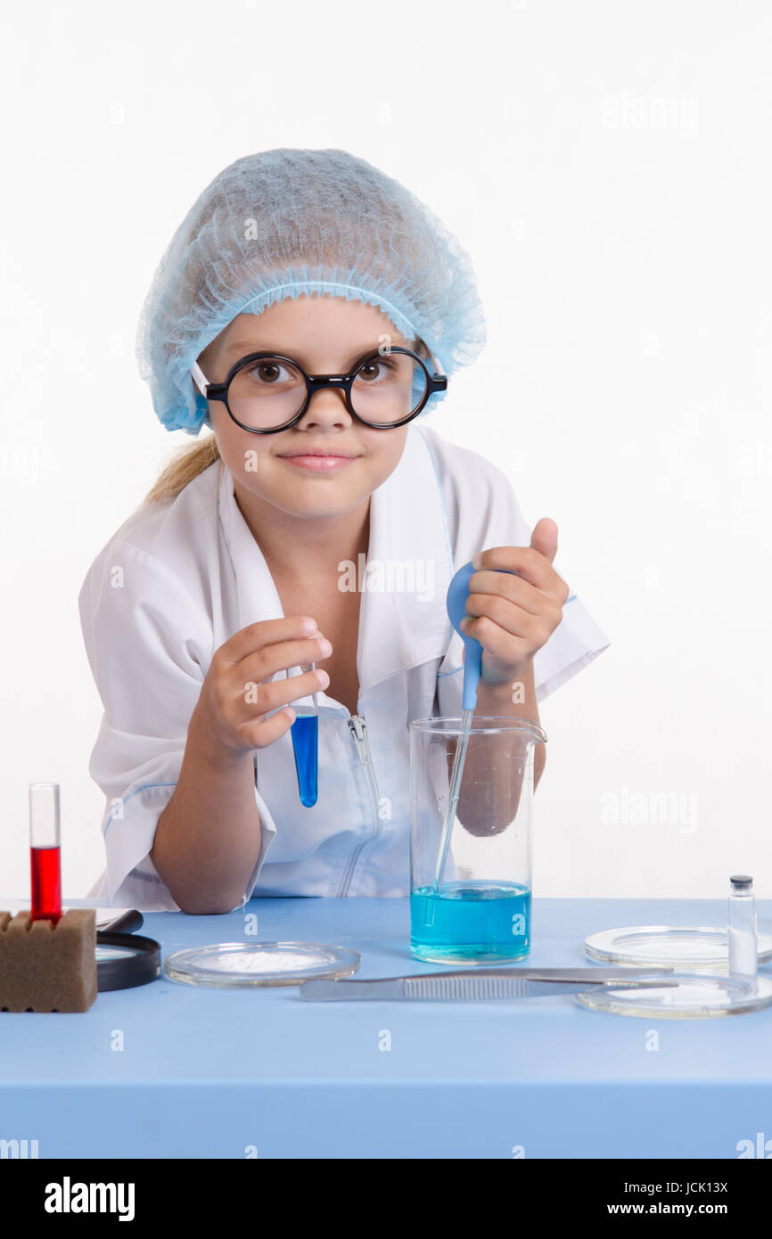 Chemist girl sitting at the table with the reagents in chemistry class ...