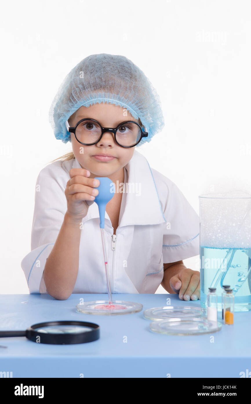 Chemist girl sitting at the table with the reagents in chemistry class ...