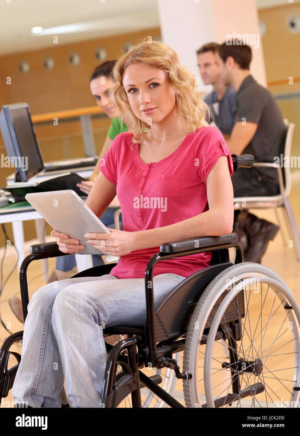 Young woman in wheelchair working in office Stock Photo - Alamy