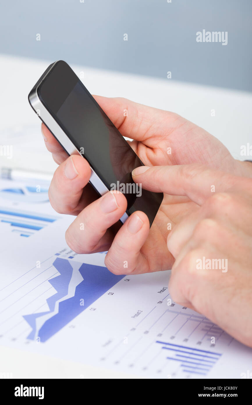 Close-up Of Person's Hand Using Cellphone Above Document Stock Photo ...