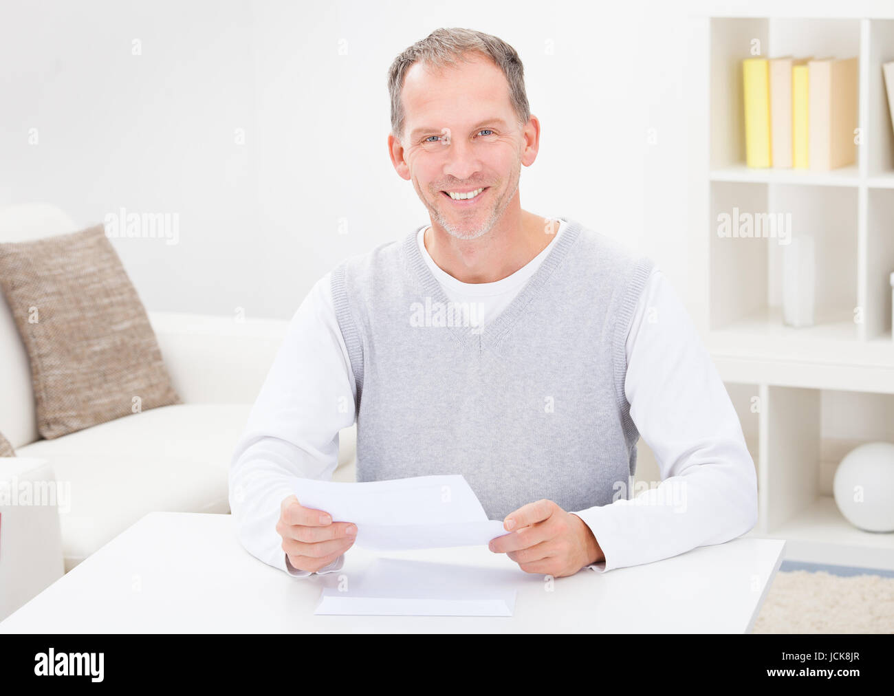 Happy Mature Man Holding Document At Home Stock Photo - Alamy