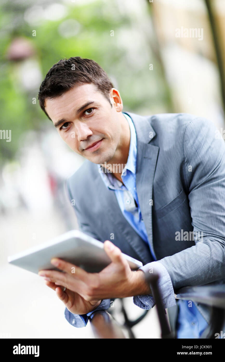 Man using electronic tablet outside in town Stock Photo - Alamy