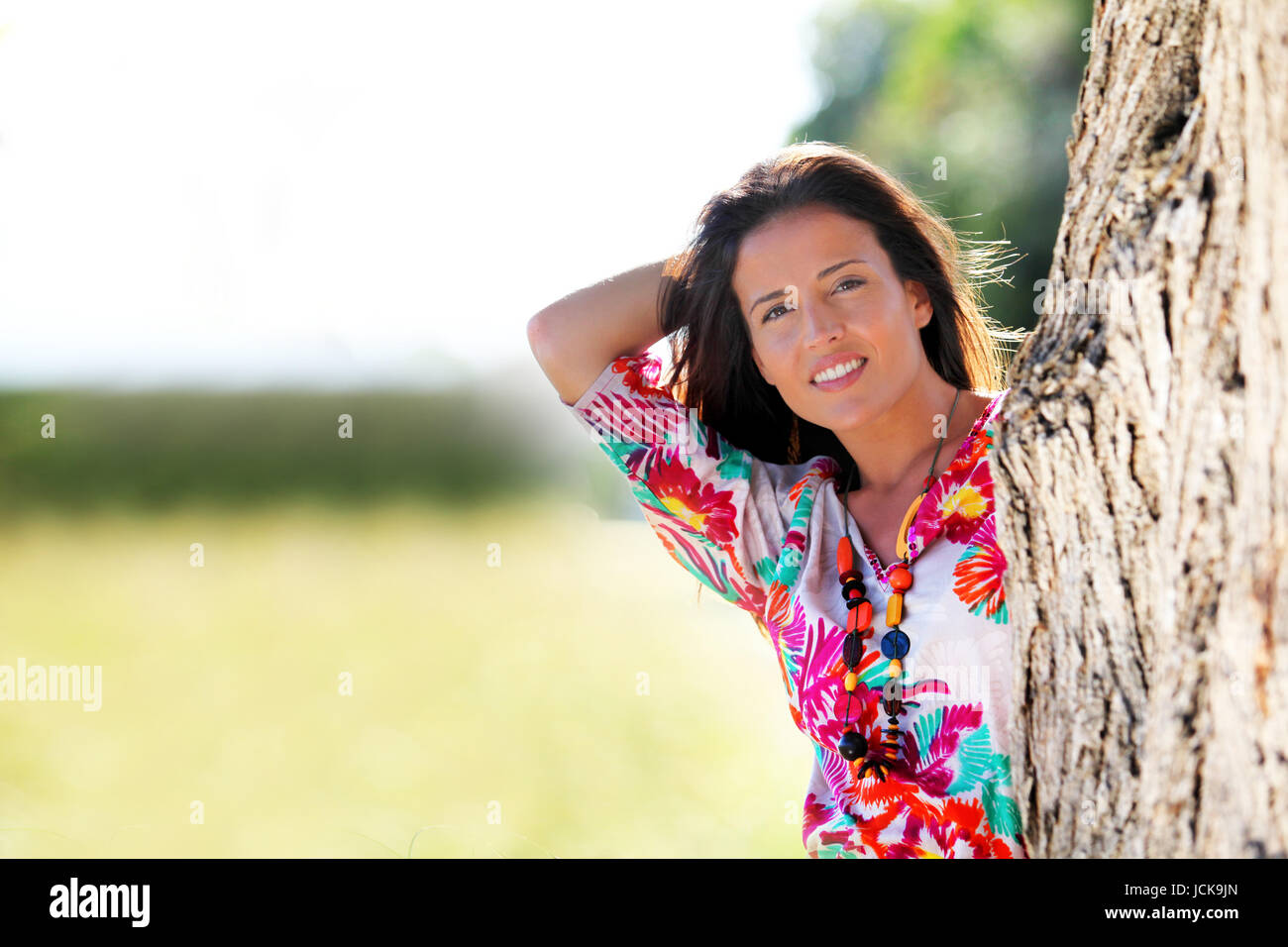 Beautiful woman standing by a tree in countryside Stock Photo - Alamy
