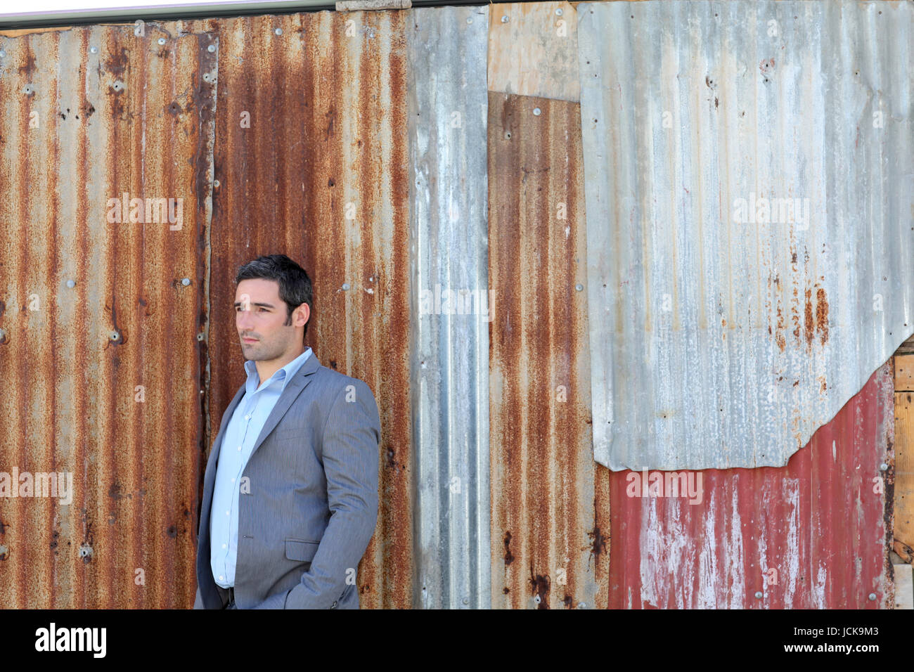 Businessman standing in front of sheet metal wall Stock Photo - Alamy