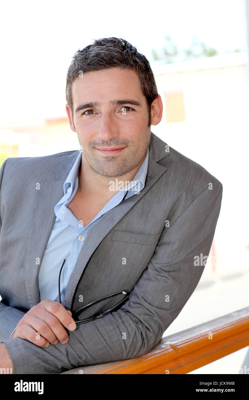 Portrait of confident salesman leaning on balustrade Stock Photo - Alamy