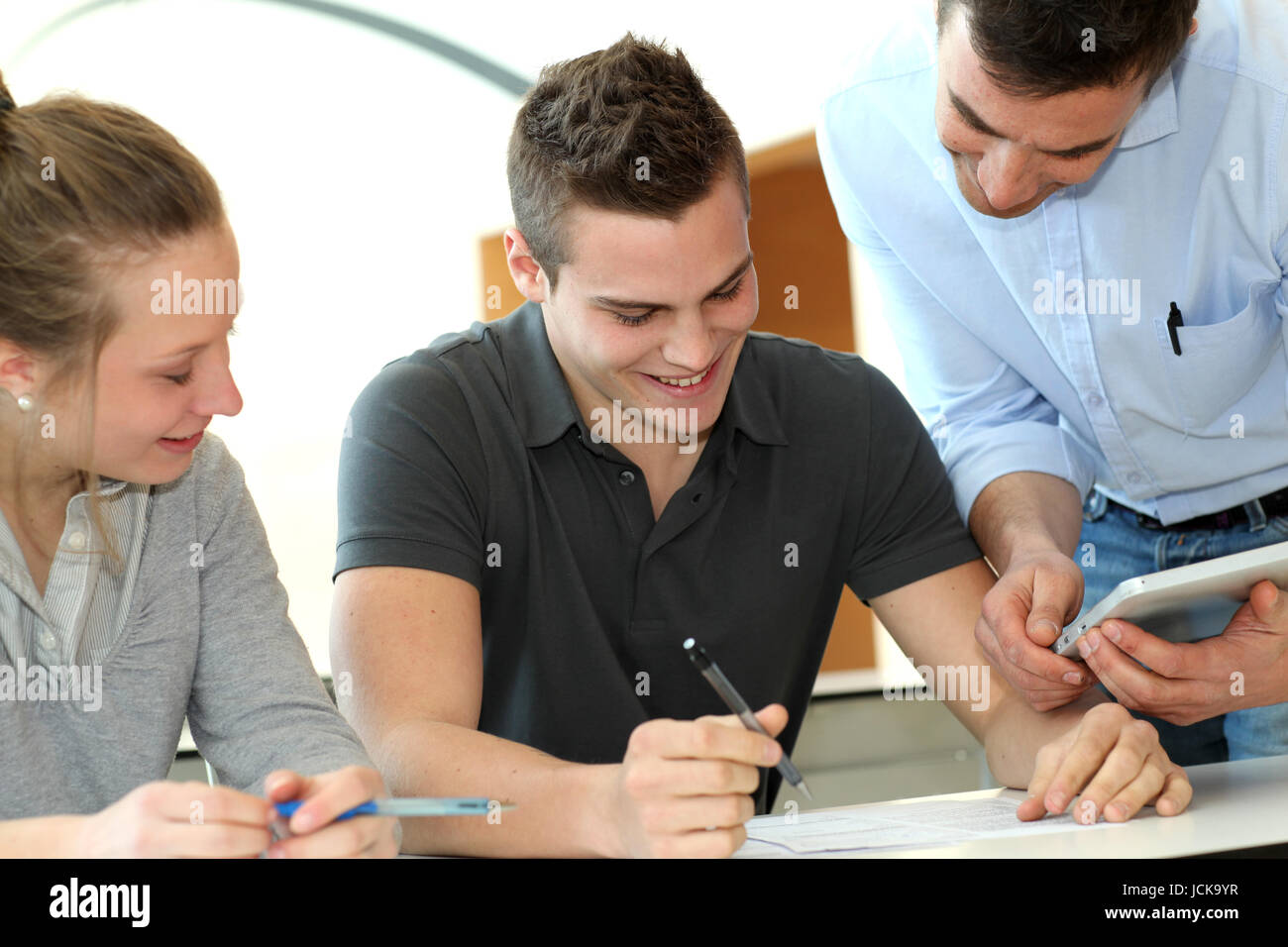 Teacher helping students with assignment Stock Photo - Alamy