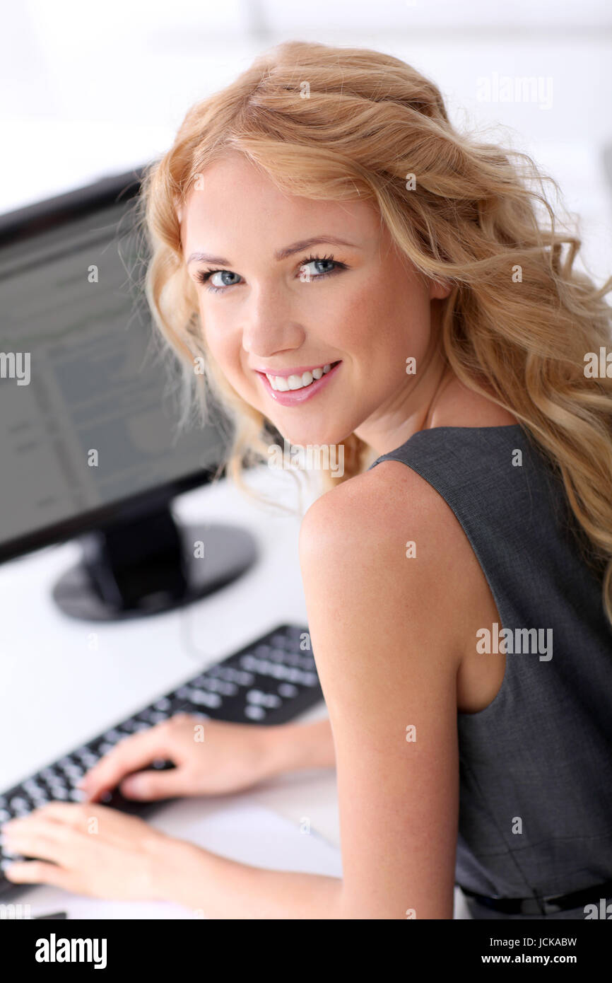 Portrait of beautiful woman sitting in front of desktop computer Stock ...