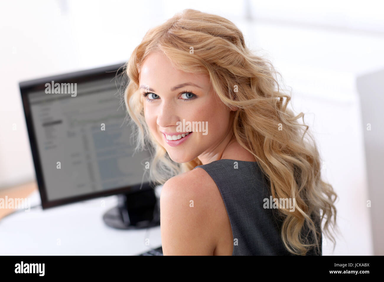 Portrait of beautiful woman sitting in front of desktop computer Stock ...