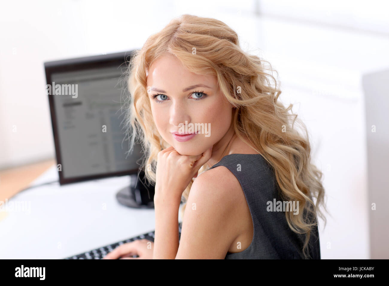 Portrait of beautiful woman sitting in front of desktop computer Stock ...