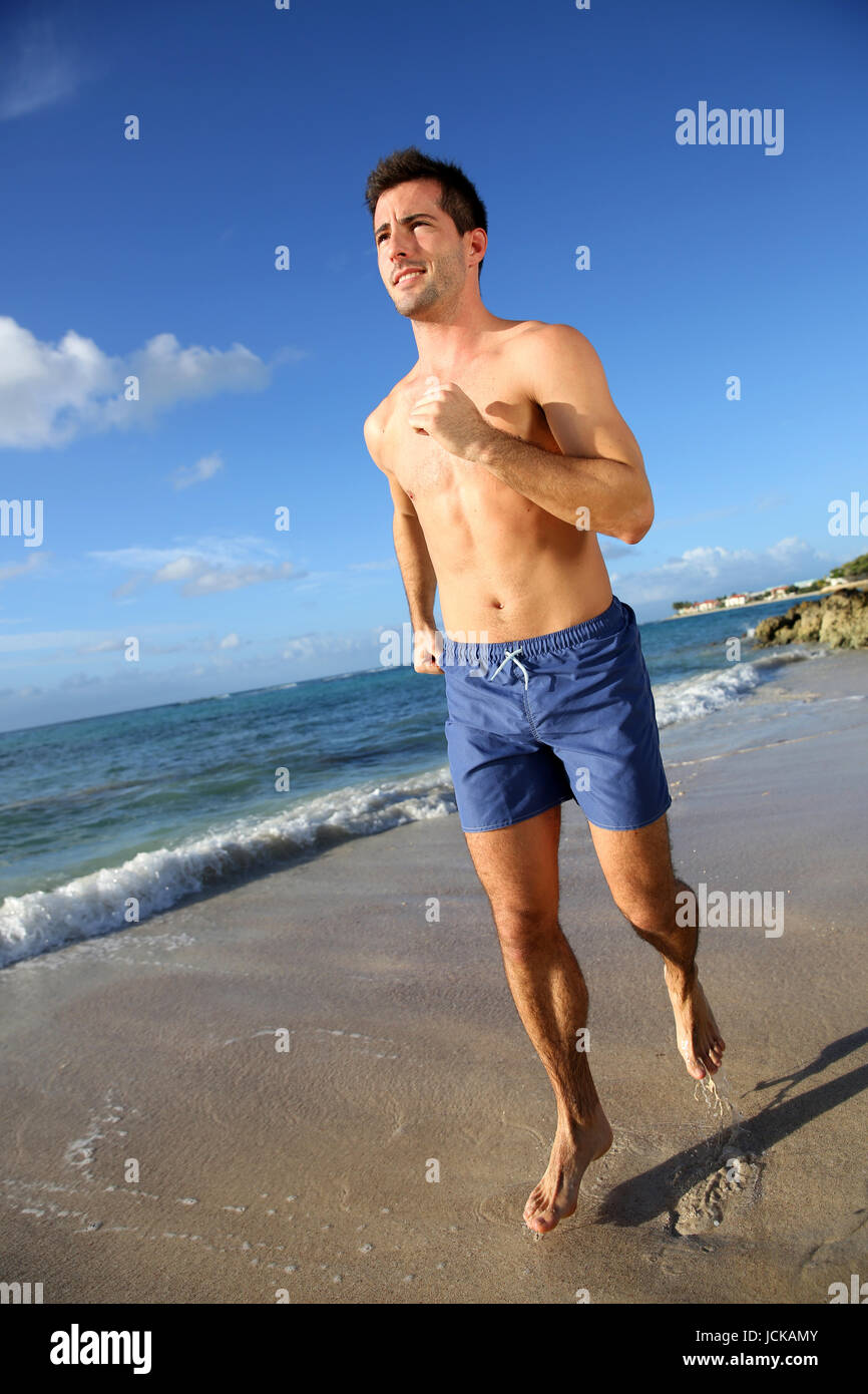 Young man running on the beach Stock Photo - Alamy
