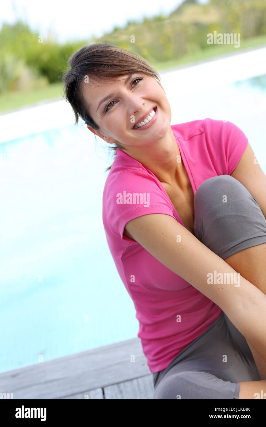 Beautiful woman sitting by pool in fitness outfit Stock Photo - Alamy