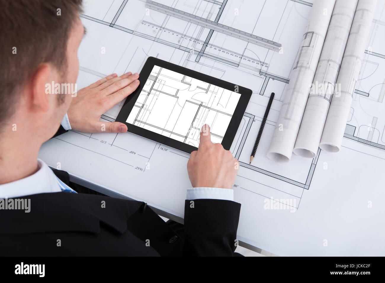 High angle view of male architect using digital tablet on blueprint in ...