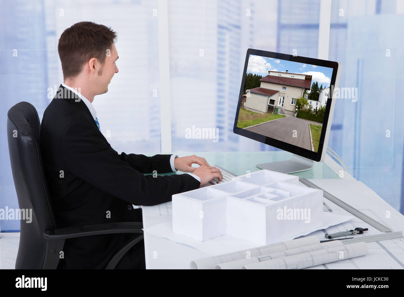 Side view of young male architect browsing property on computer in ...