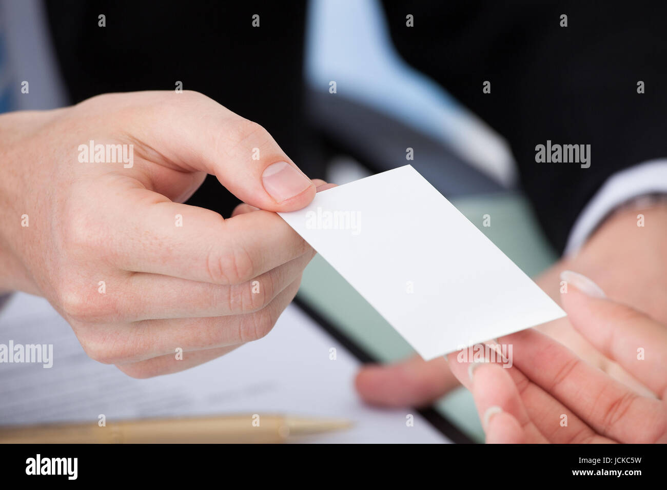 Cropped image of businessman giving visiting card to woman in office ...