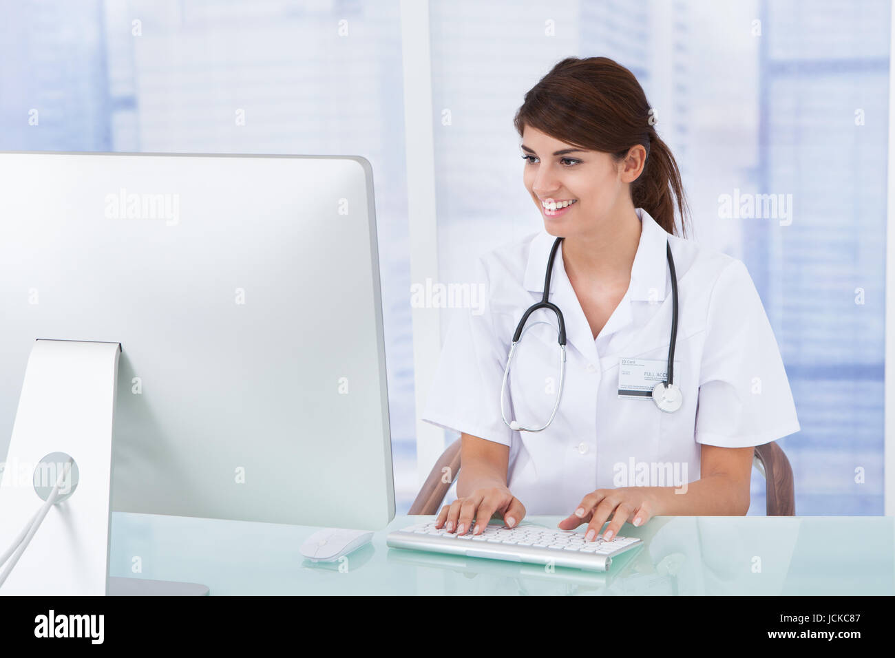 Portrait of young female doctor using computer at desk in clinic Stock ...