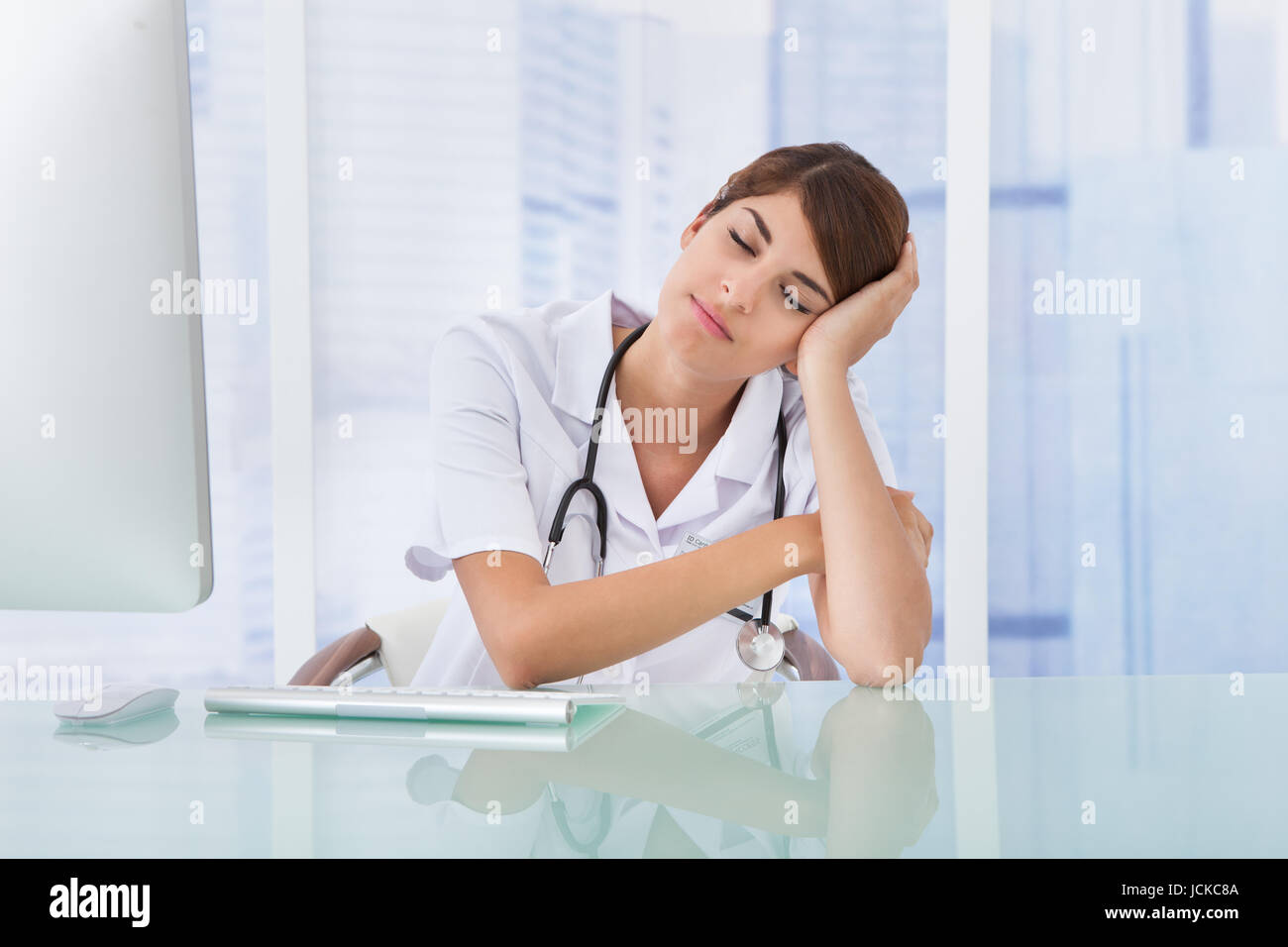 Tired young female doctor at desk in hospital Stock Photo - Alamy