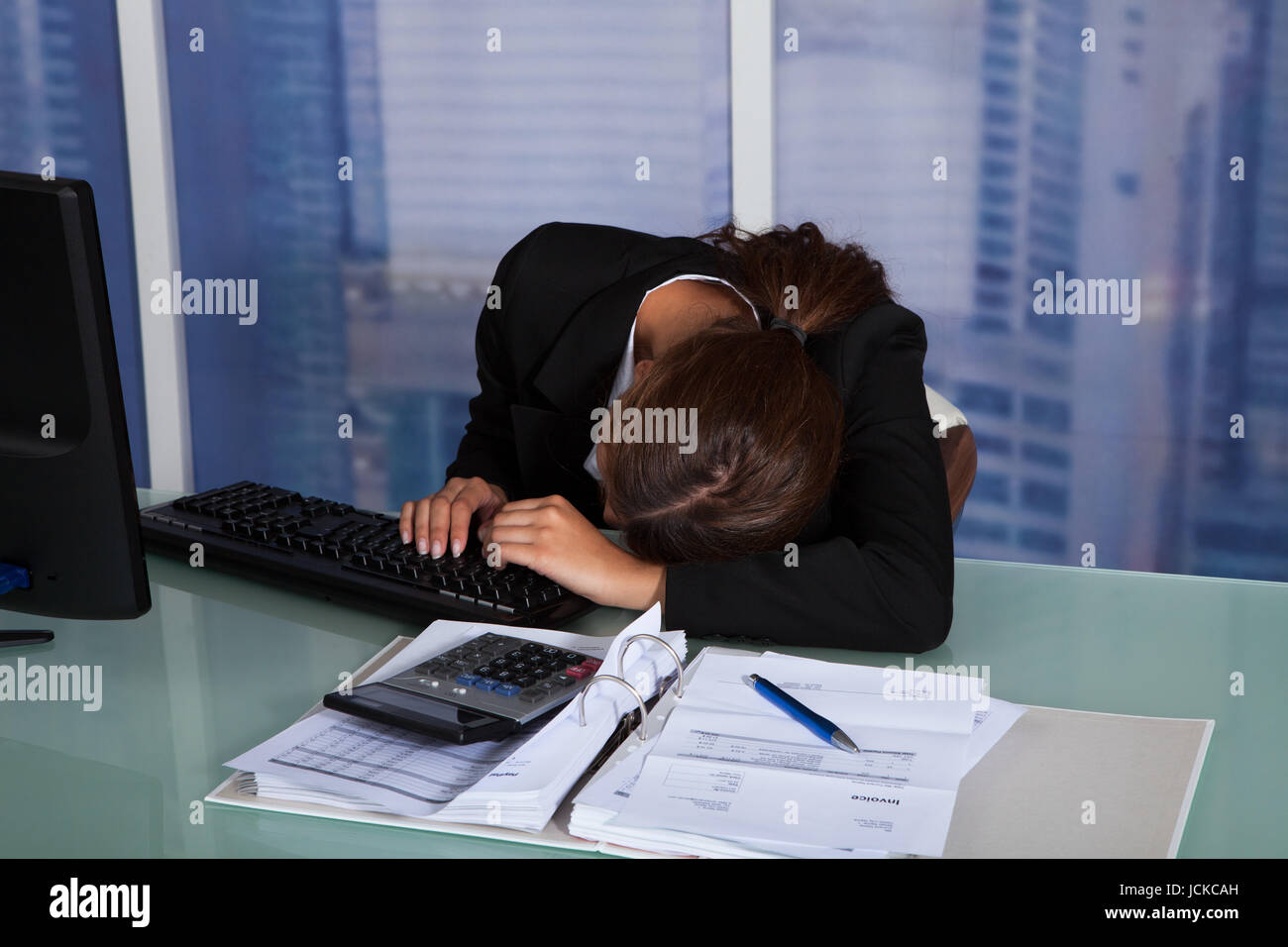 Overworked young businesswoman leaning at computer desk in office Stock ...