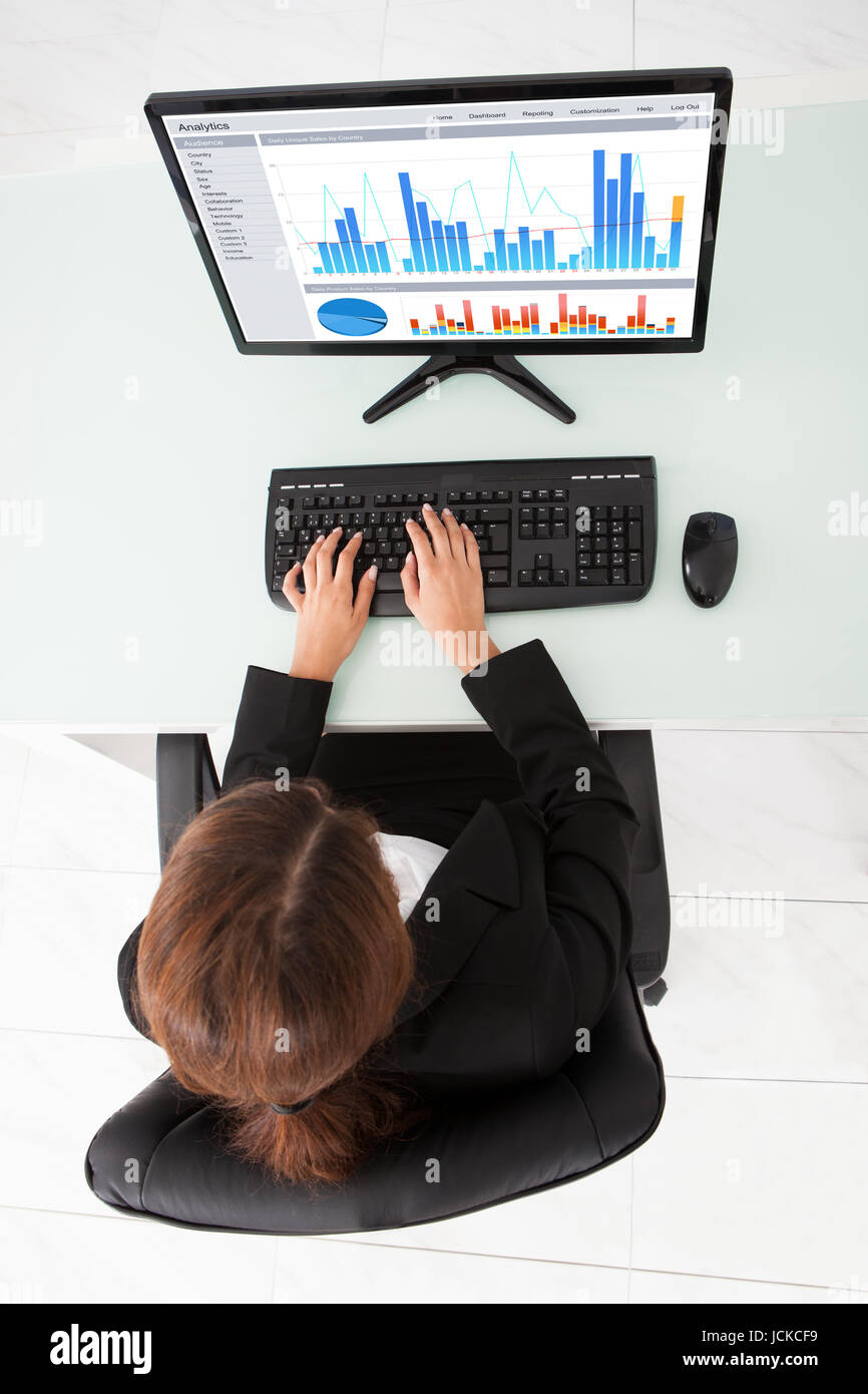 High angle view of businesswoman making financial charts on computer at ...
