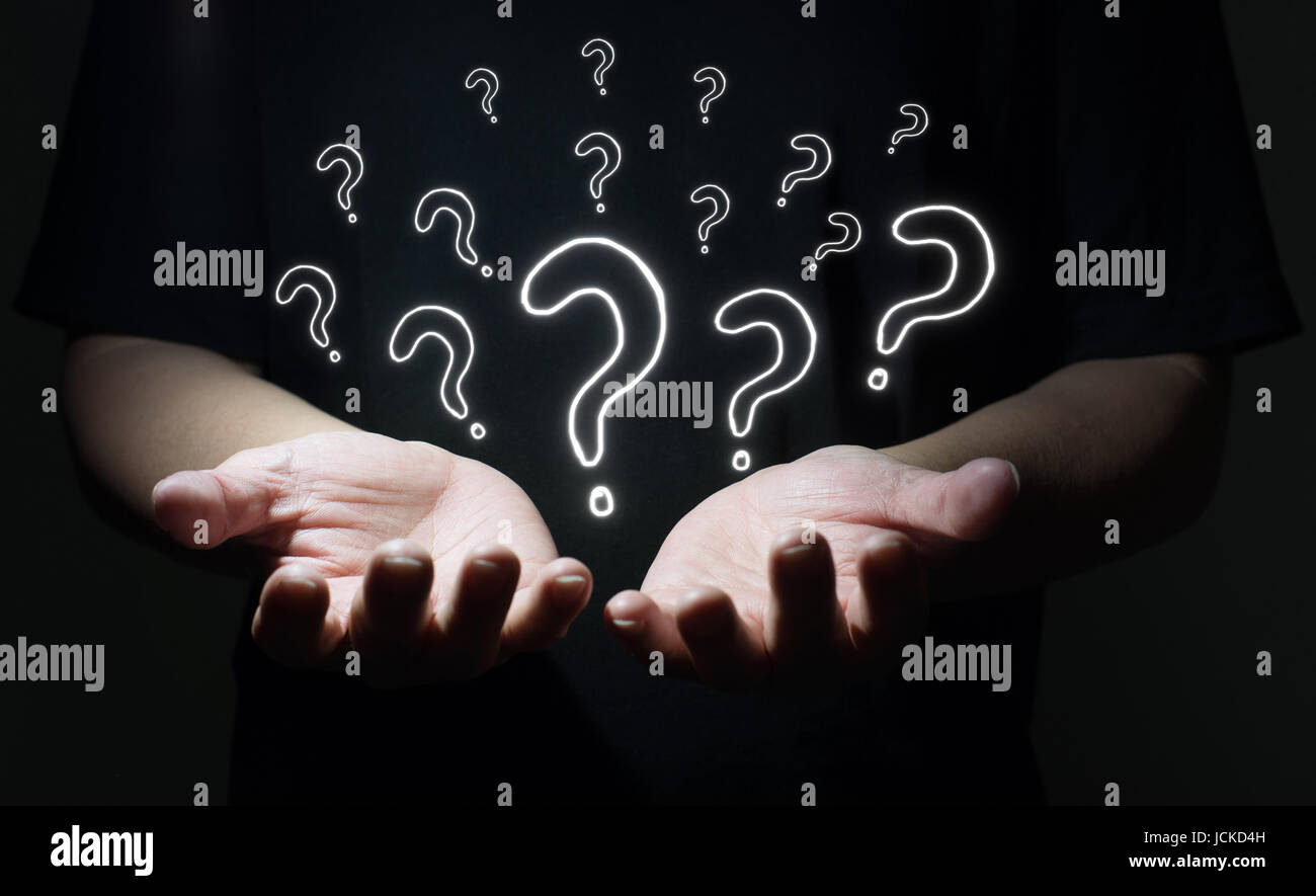 Businessman holding drawn question marks in his hand with dark ...