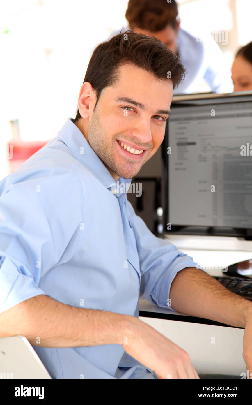 Smiling trader in front of desktop computer Stock Photo - Alamy