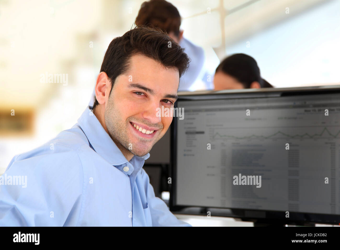 Smiling trader in front of desktop computer Stock Photo - Alamy