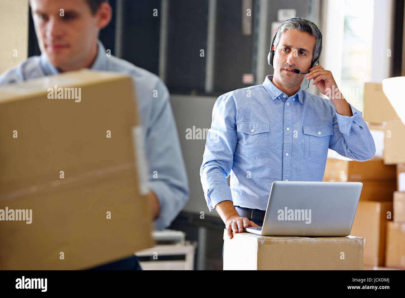 Manager Using Headset In Distribution Warehouse Stock Photo - Alamy