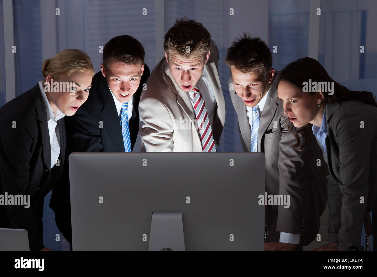 Surprised young business people looking at computer monitor in office ...