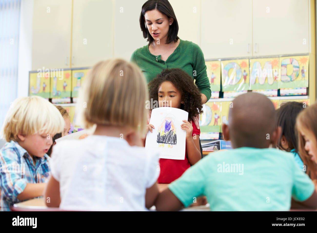 Elementary Pupil Showing Drawing To Classmates In Classroom Stock Photo ...
