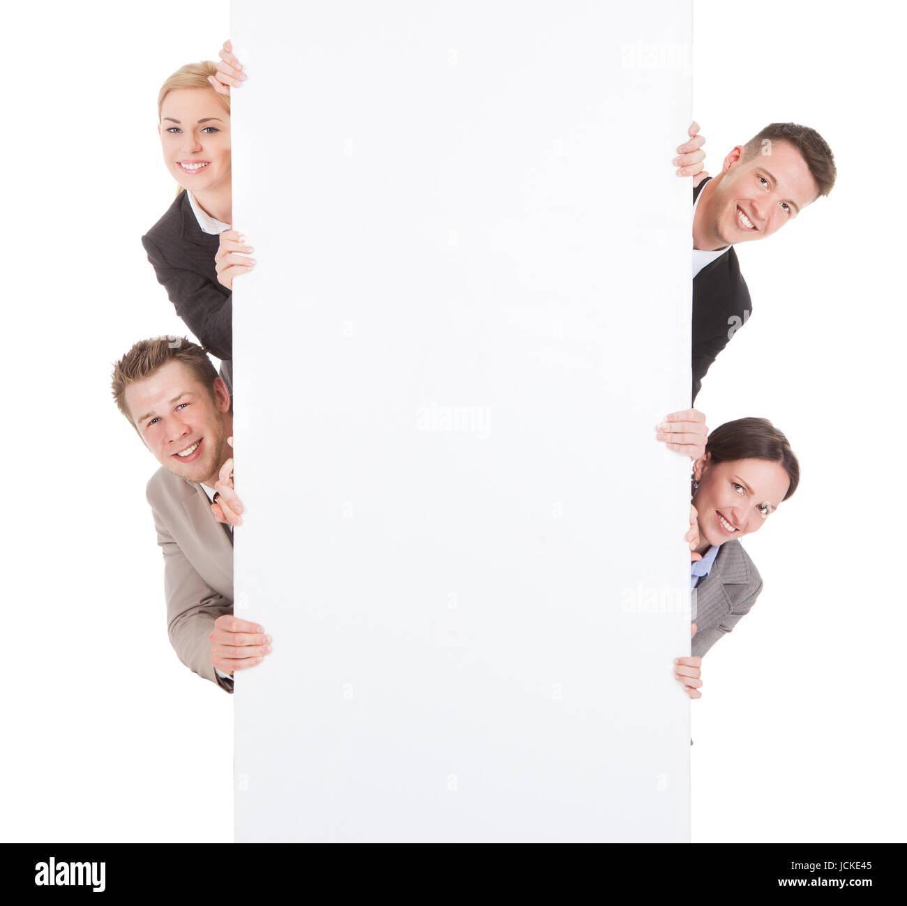 Portrait of smiling young business people looking from behind the blank ...