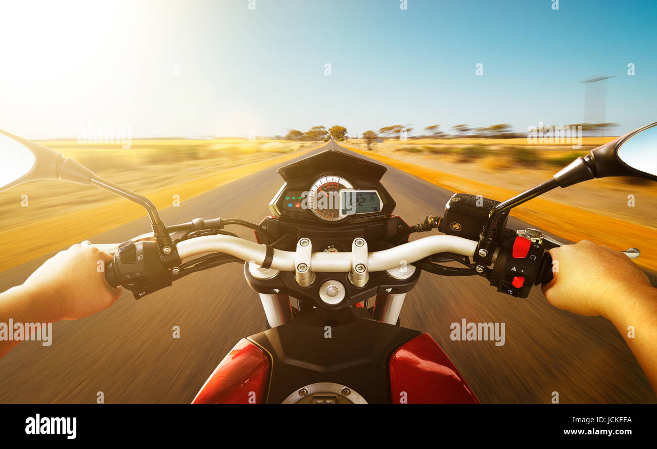 Biker driving a motorcycle rides along the country road , morning scene ...