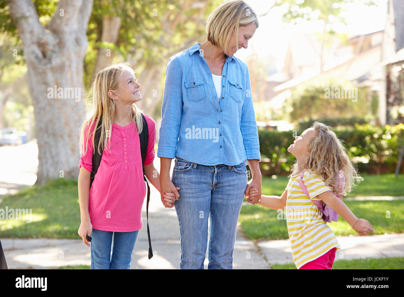 Mother And Daughters Walking To School On Suburban Street Stock Photo ...