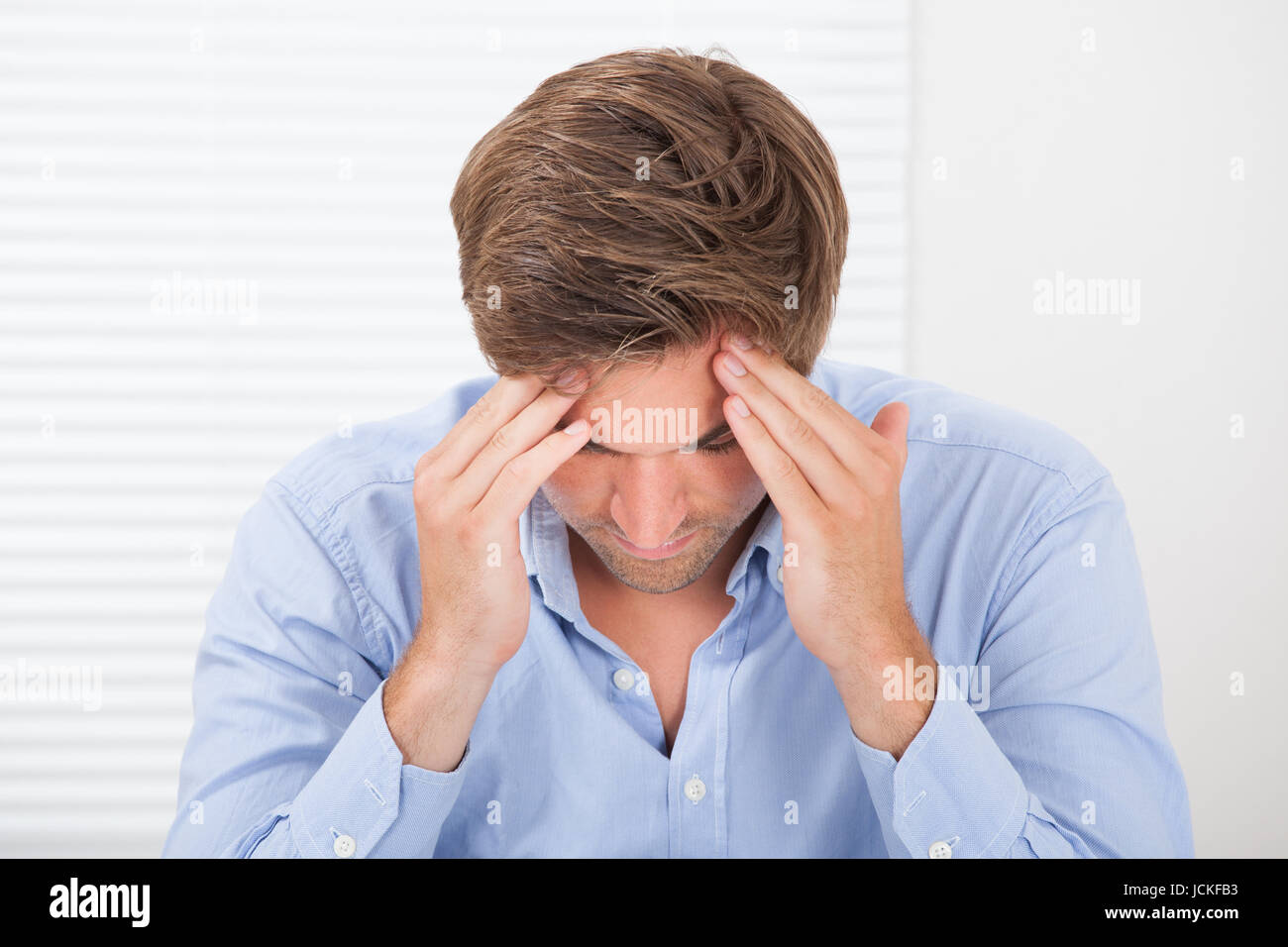 Mid adult businessman suffering from headache in office Stock Photo - Alamy
