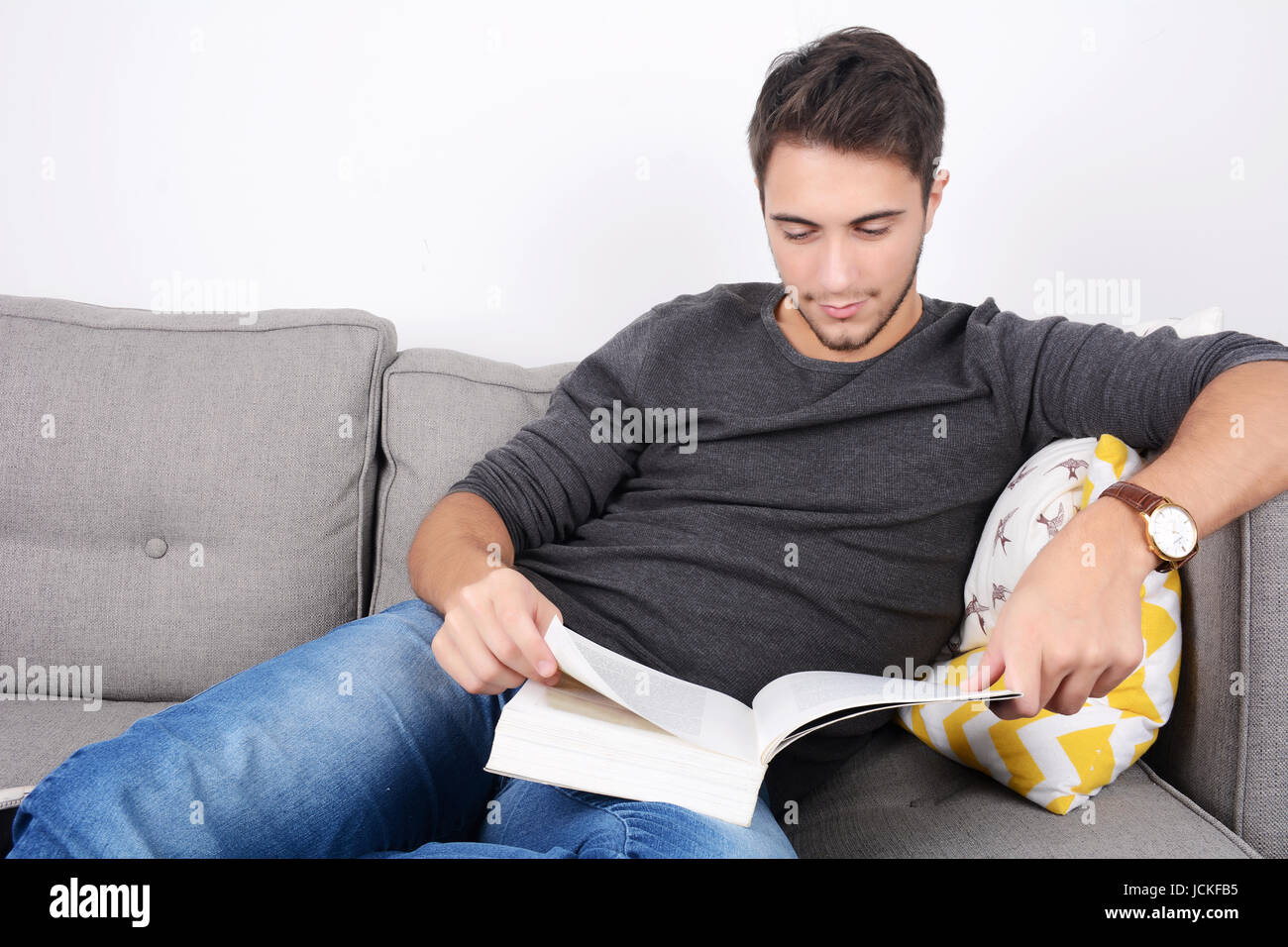 Attractive young man relaxed and reading a book. Indoors Stock Photo ...