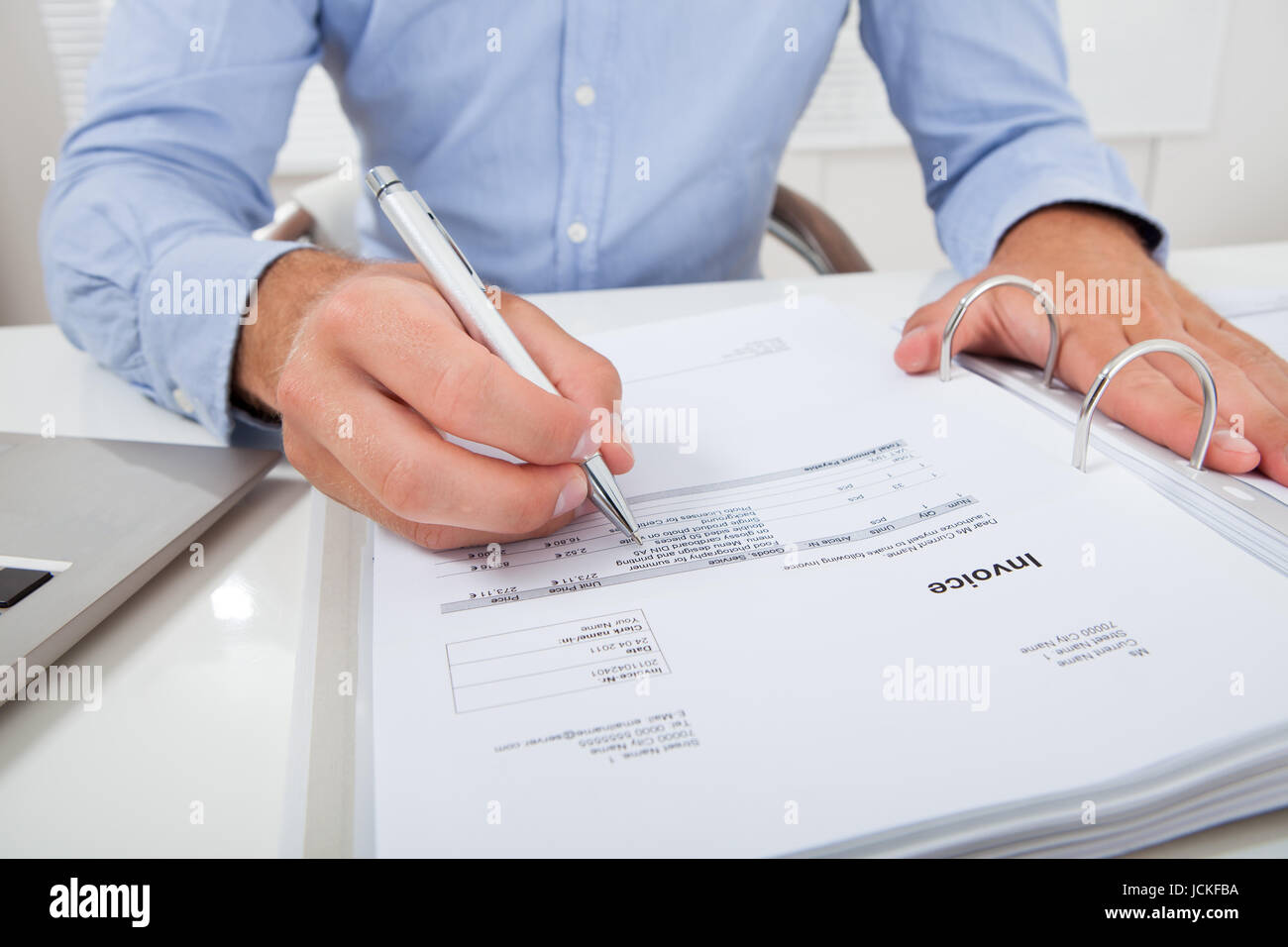 Cropped image of businessman calculating invoice at desk in office ...
