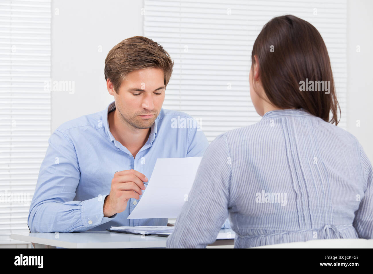 Mid adult businessman checking resume of female candidate during ...
